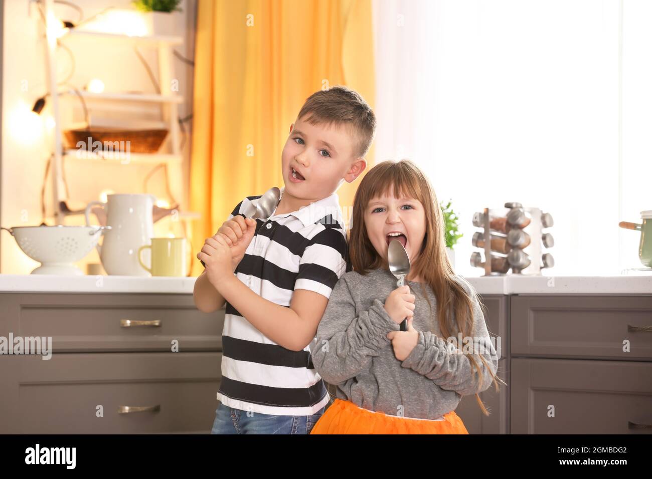 Cute little children using spoons as microphone in kitchen Stock Photo ...