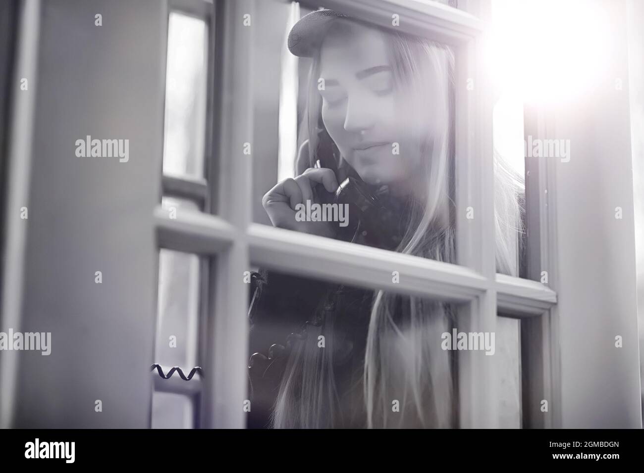 Beautiful young girl in a phone booth. The girl is talking on the phone ...