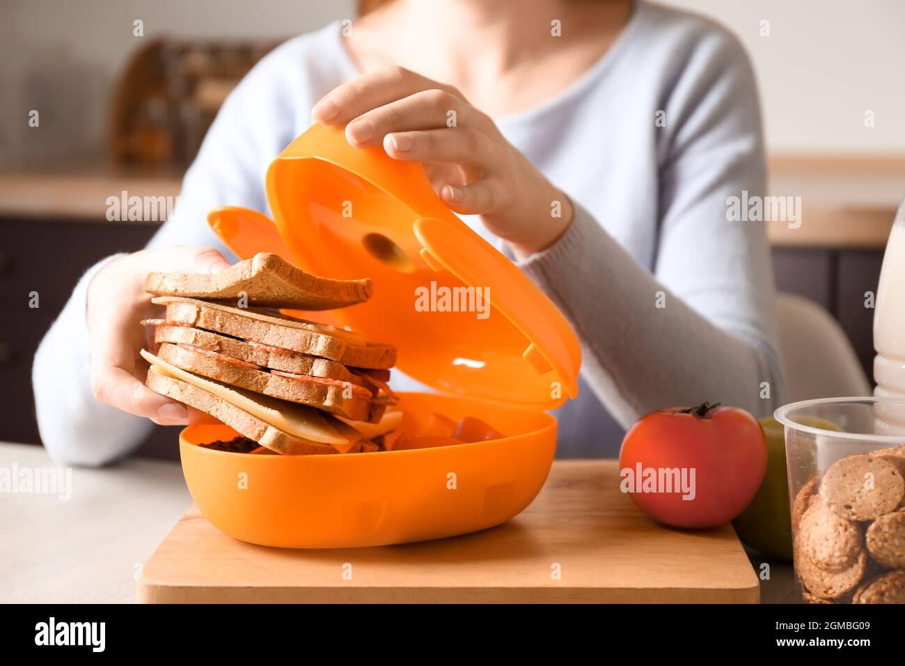 Mother putting food into school lunch box on table Stock Photo - Alamy