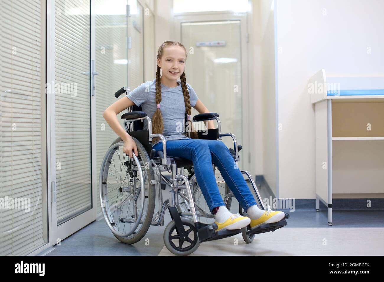 Little girl sitting in wheelchair indoors Stock Photo - Alamy