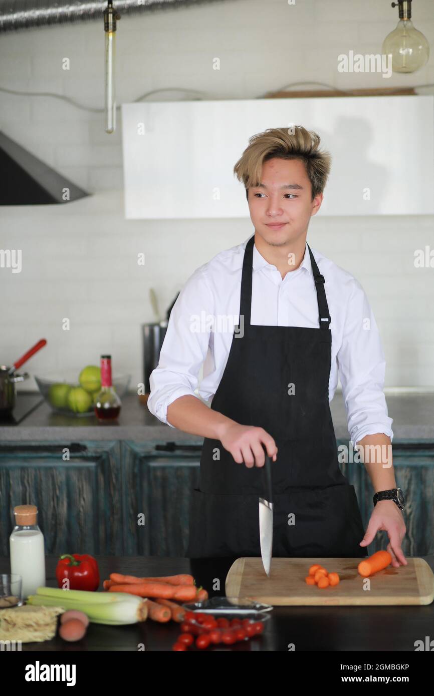A young Asian cook in the kitchen prepares food in a cook suit Stock ...