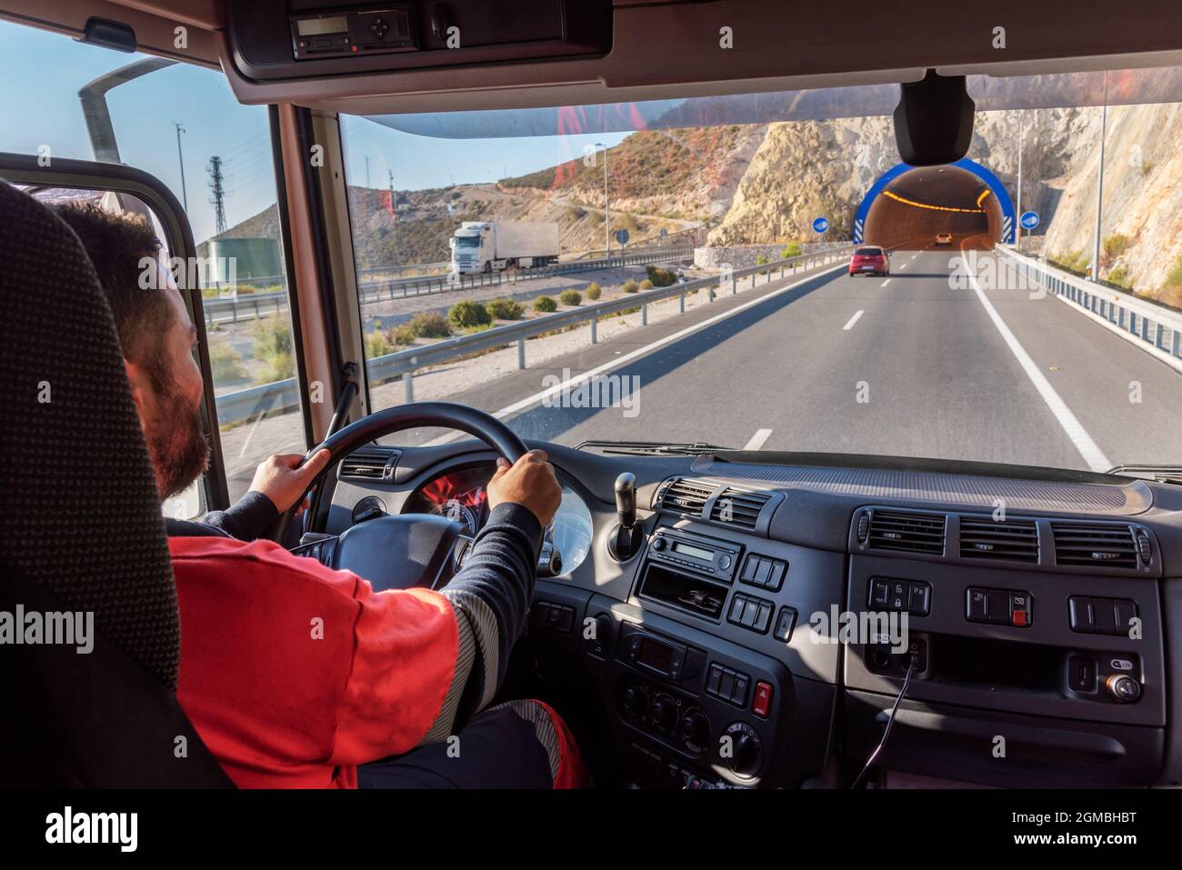 Truck driver, seen from inside the cab, driving on the highway and at ...