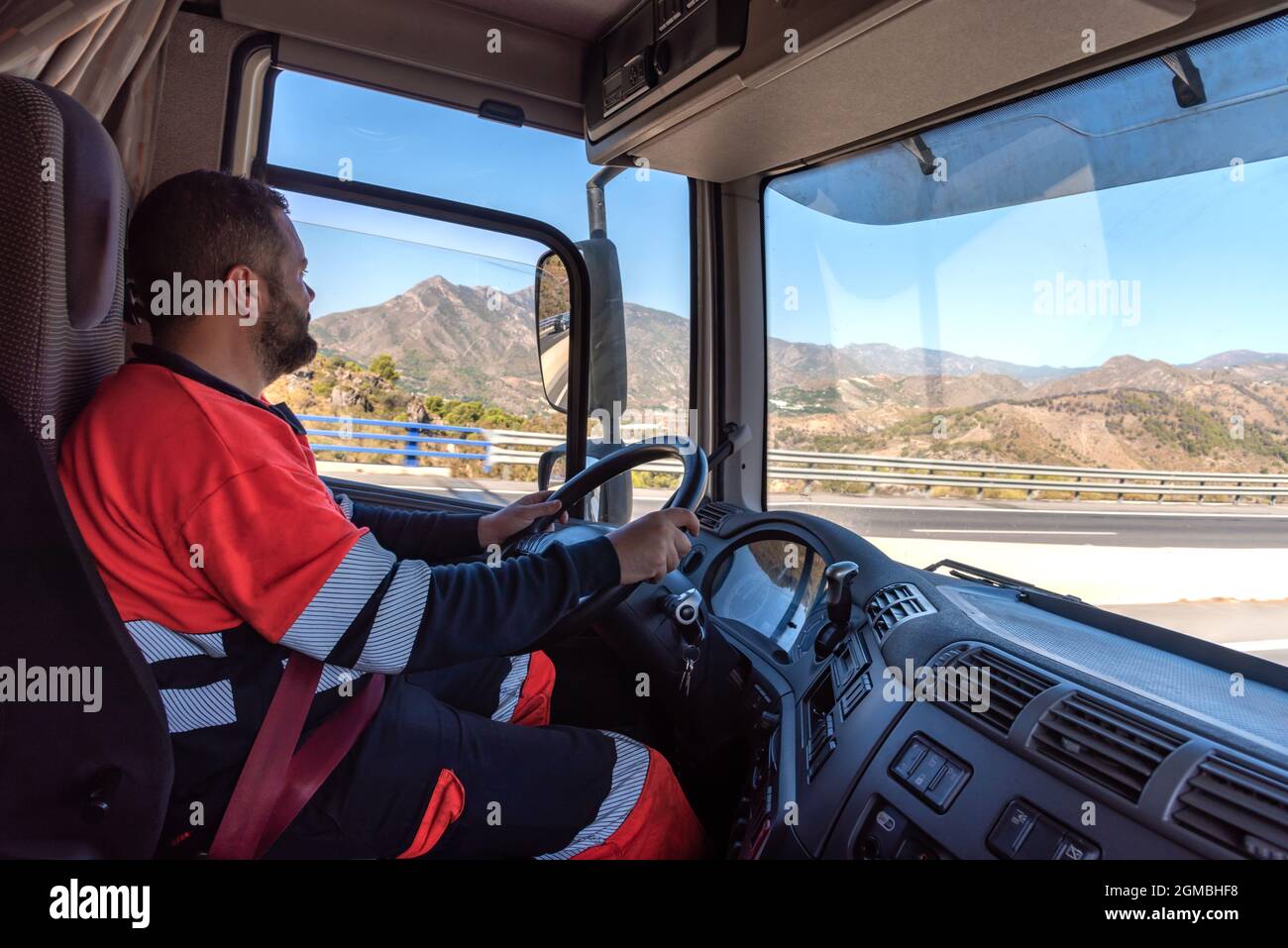 Truck driver in the driving position with both hands holding the ...