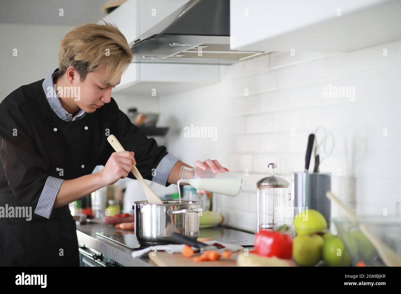 A young Asian cook in the kitchen prepares food in a cook suit Stock ...