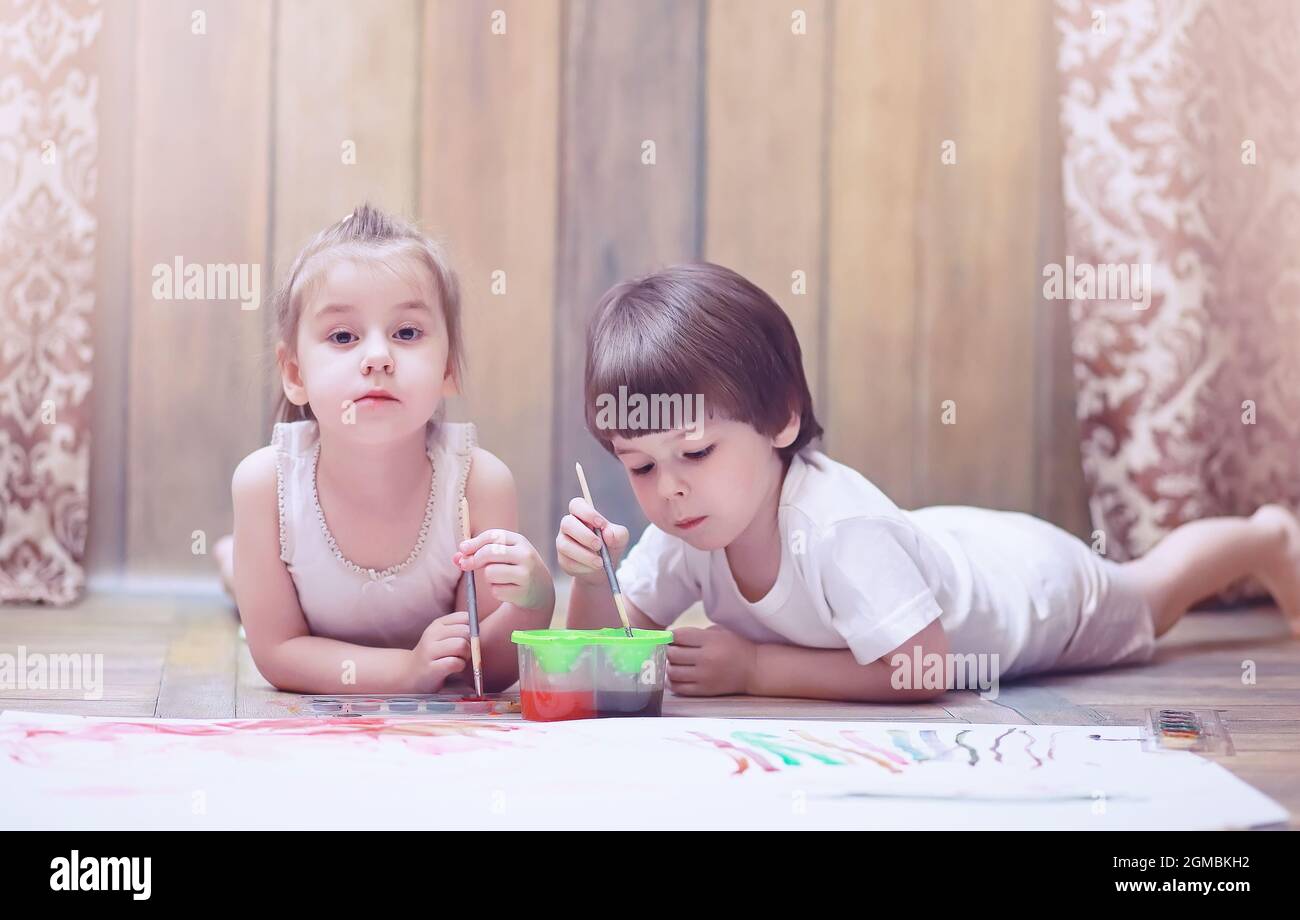Little children paint on a large sheet of paper on the floor Stock ...