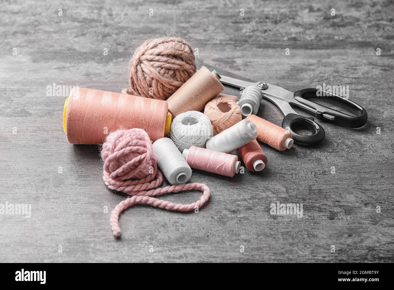 Different types of threads with scissors on grey background Stock Photo ...
