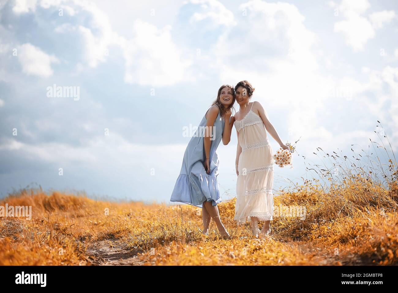 Two beautiful girls in dresses in autumn field have fun Stock Photo - Alamy