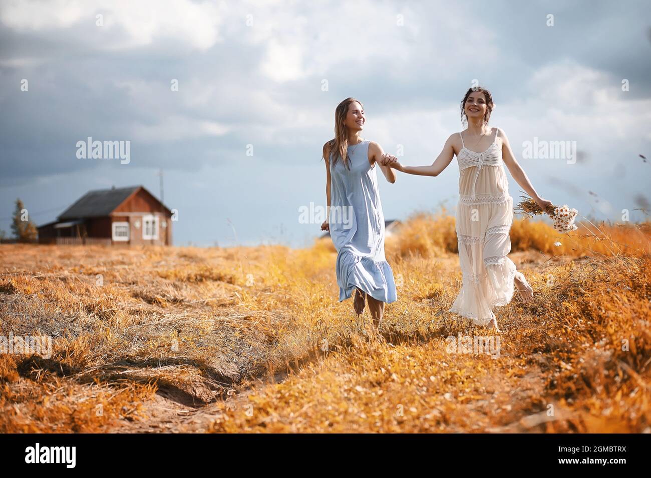 Two beautiful girls in dresses in autumn field have fun Stock Photo - Alamy