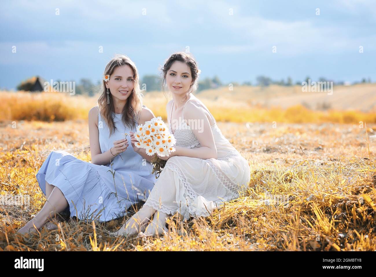 Two beautiful girls in dresses in autumn field have fun Stock Photo - Alamy