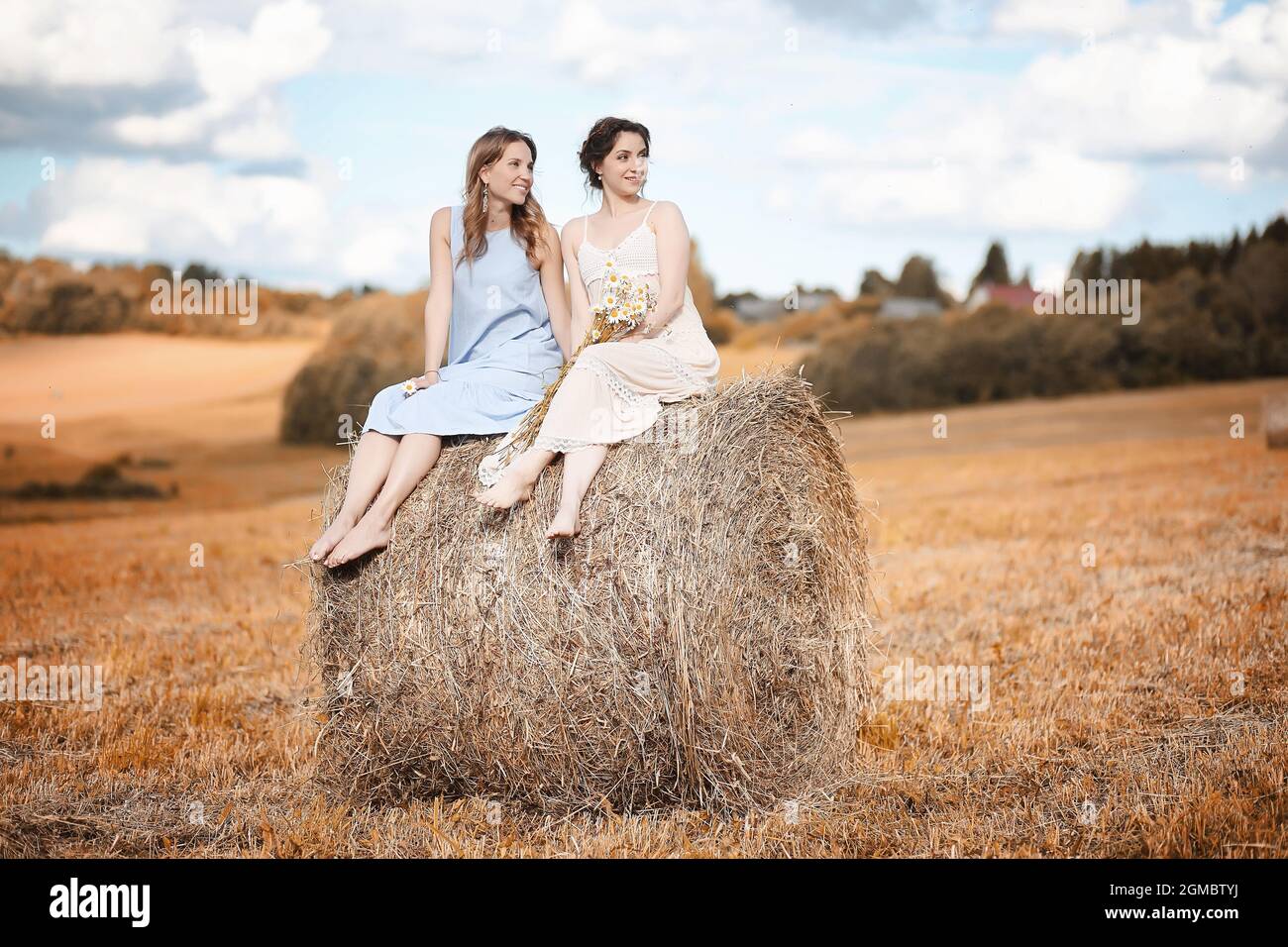 Two beautiful girls in dresses in autumn field have fun Stock Photo - Alamy