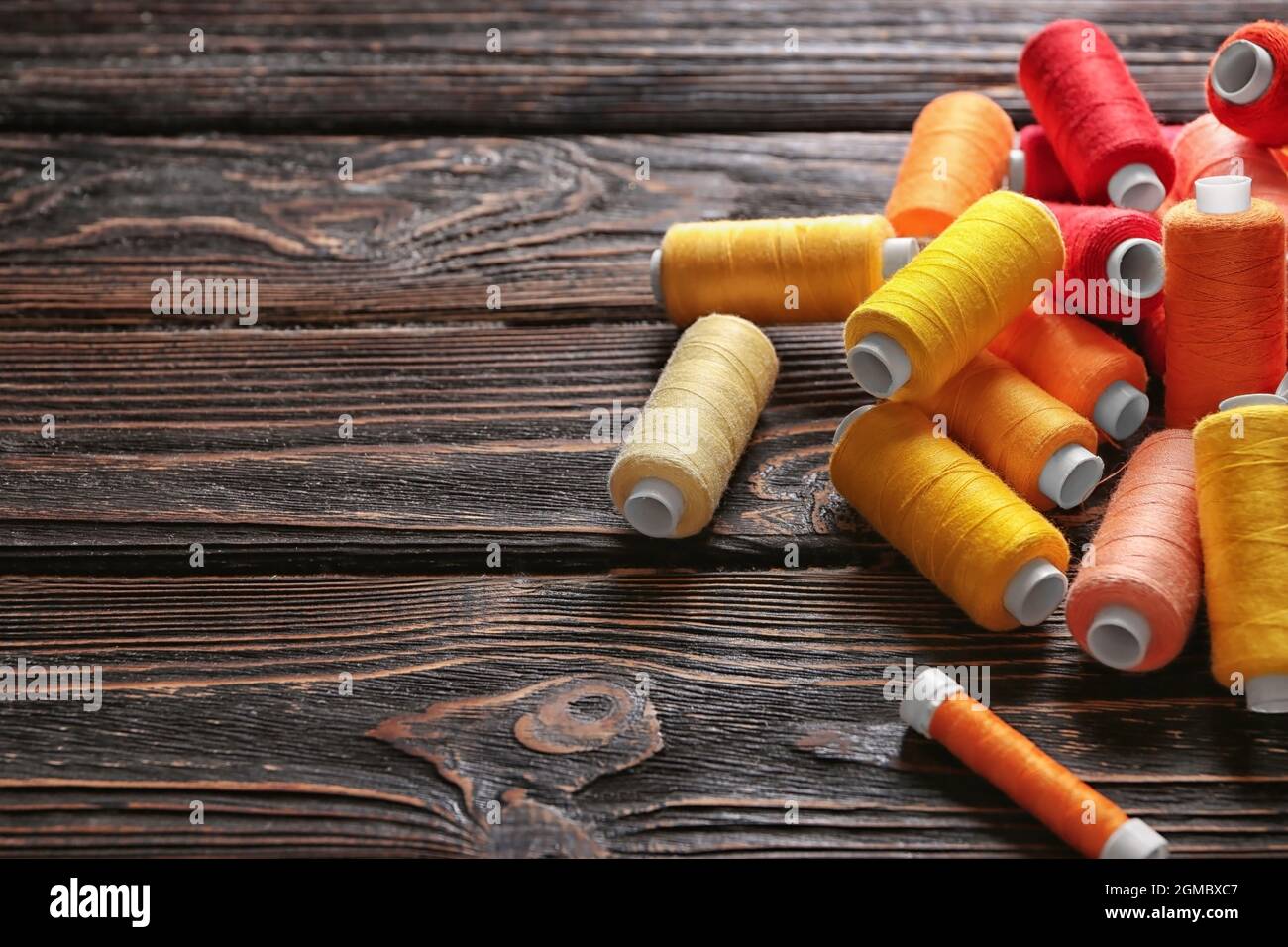Set of color sewing threads on wooden background Stock Photo - Alamy