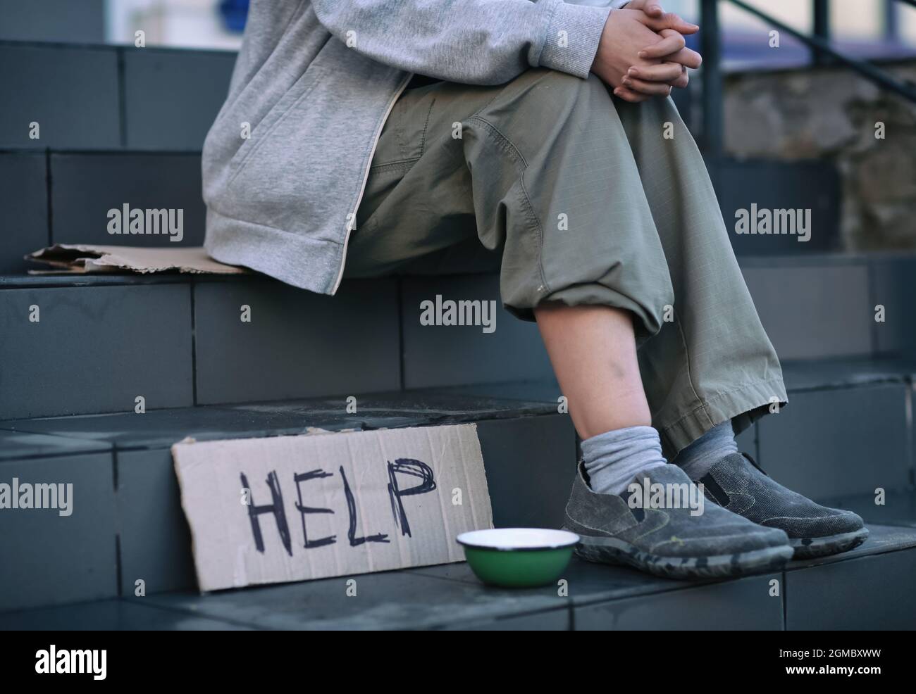 Homeless poor woman sitting on stairs near empty bowl and piece of ...