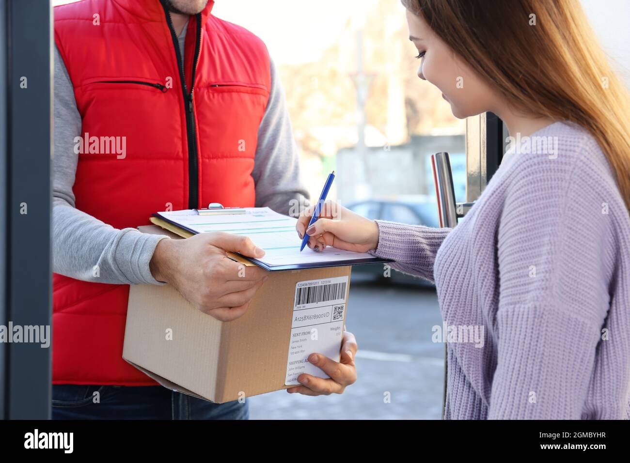 Woman signing for parcel delivery at doorway Stock Photo - Alamy