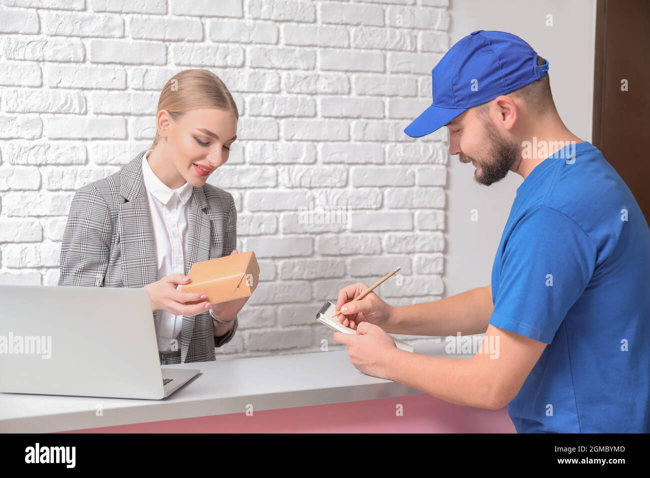 Female receptionist receiving parcel at workplace Stock Photo - Alamy