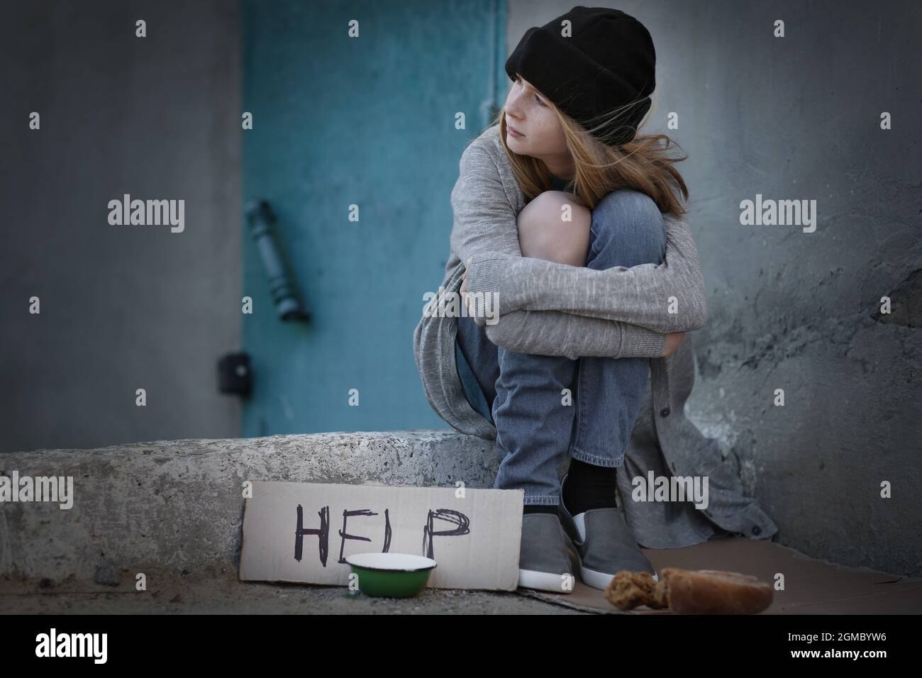 Homeless poor teenage girl sitting outdoors near empty bowl and piece ...