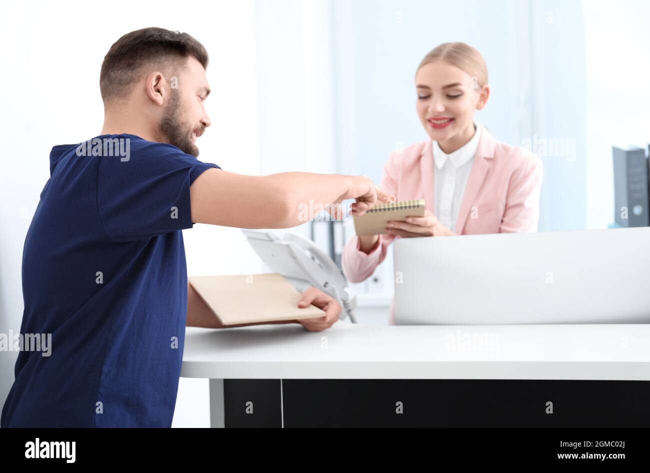 Female receptionist receiving parcel at workplace Stock Photo - Alamy