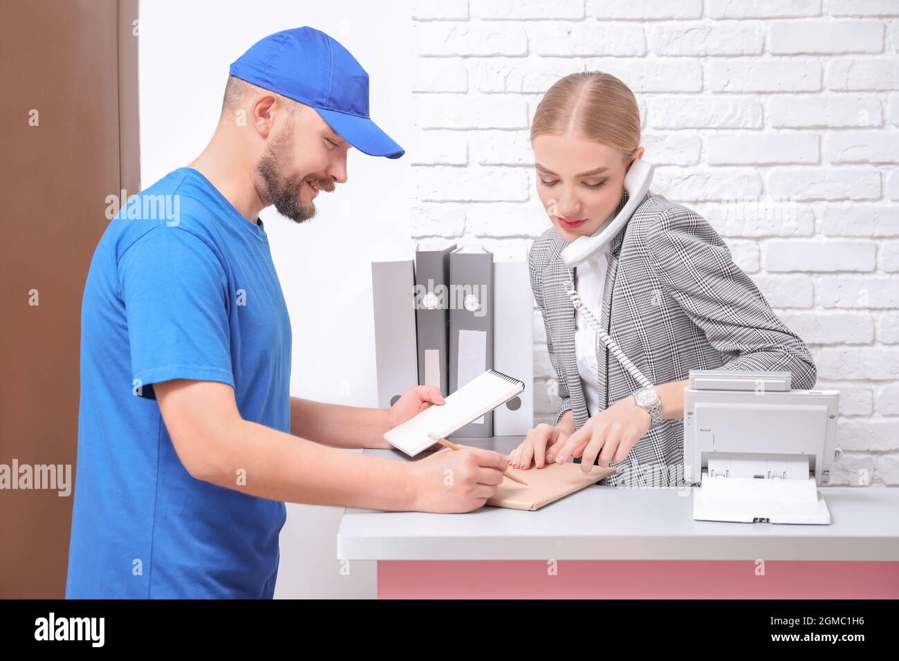 Female receptionist receiving parcel at workplace Stock Photo - Alamy