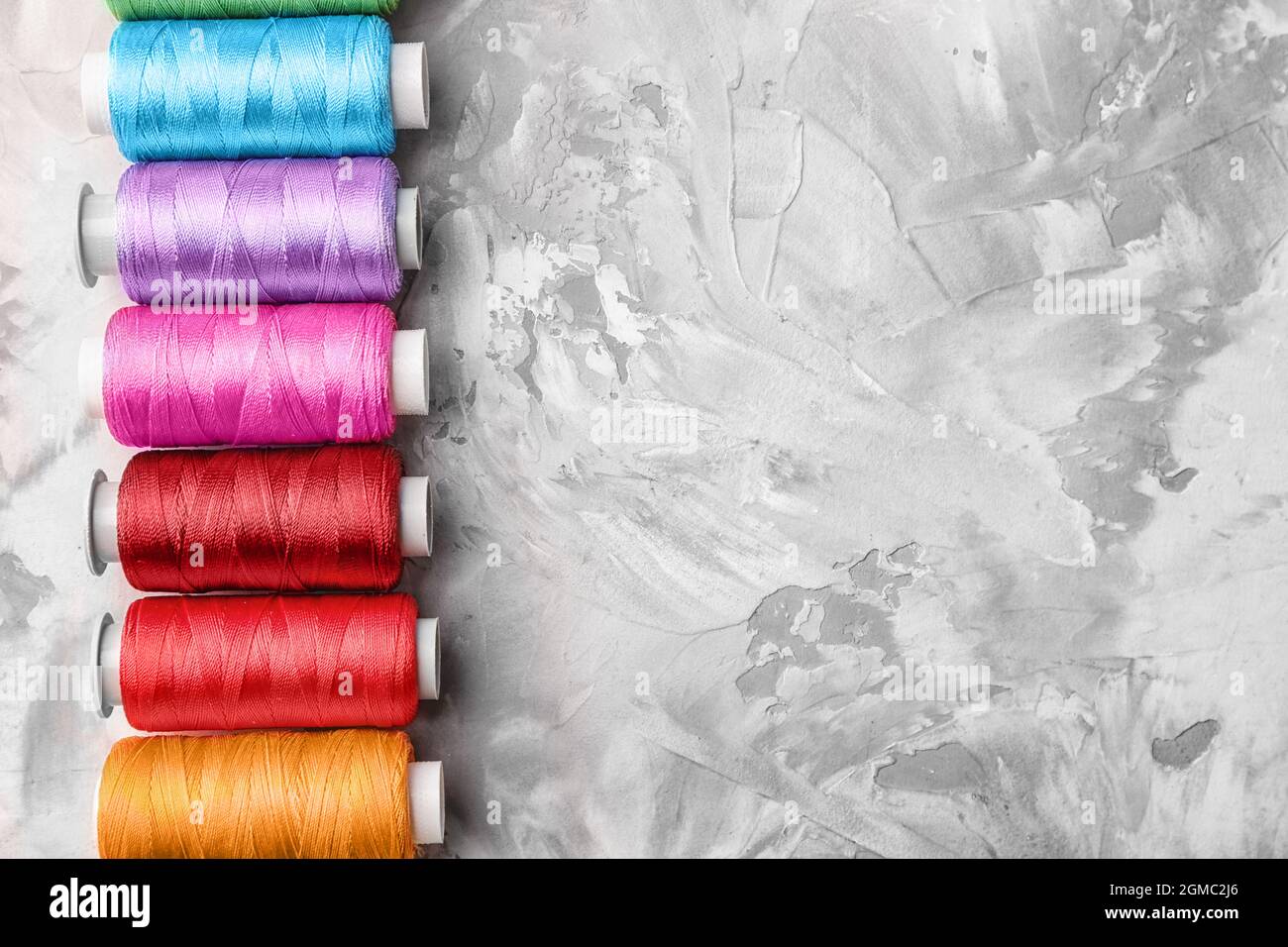 Colorful sewing threads on grey background Stock Photo - Alamy