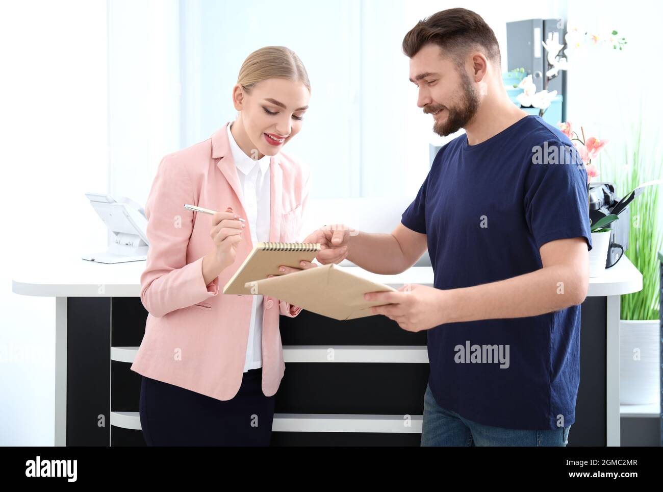 Female receptionist receiving parcel at workplace Stock Photo - Alamy