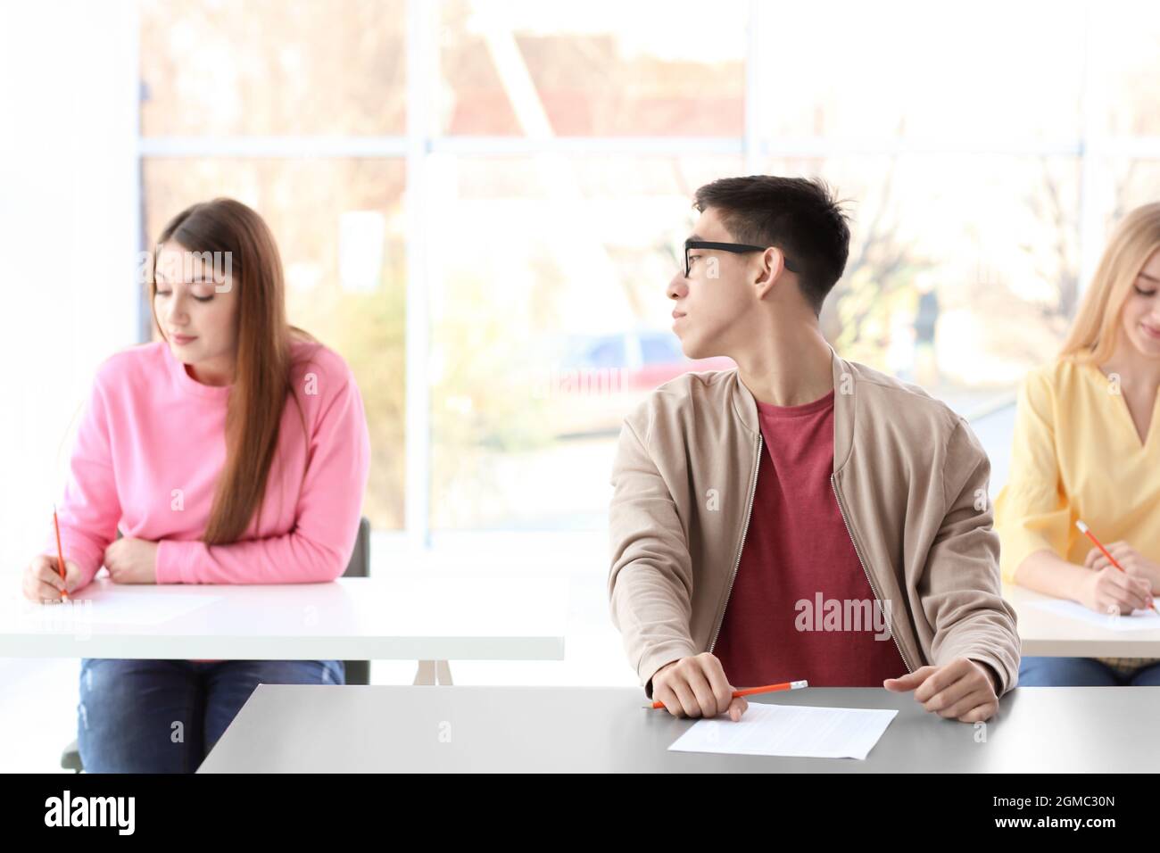 Asian student trying to copy answers of classmate at exam Stock Photo ...
