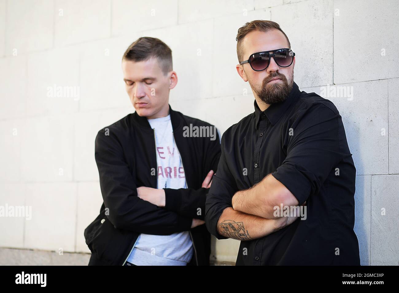 Two men in sunglasses against a brick wall background Stock Photo - Alamy