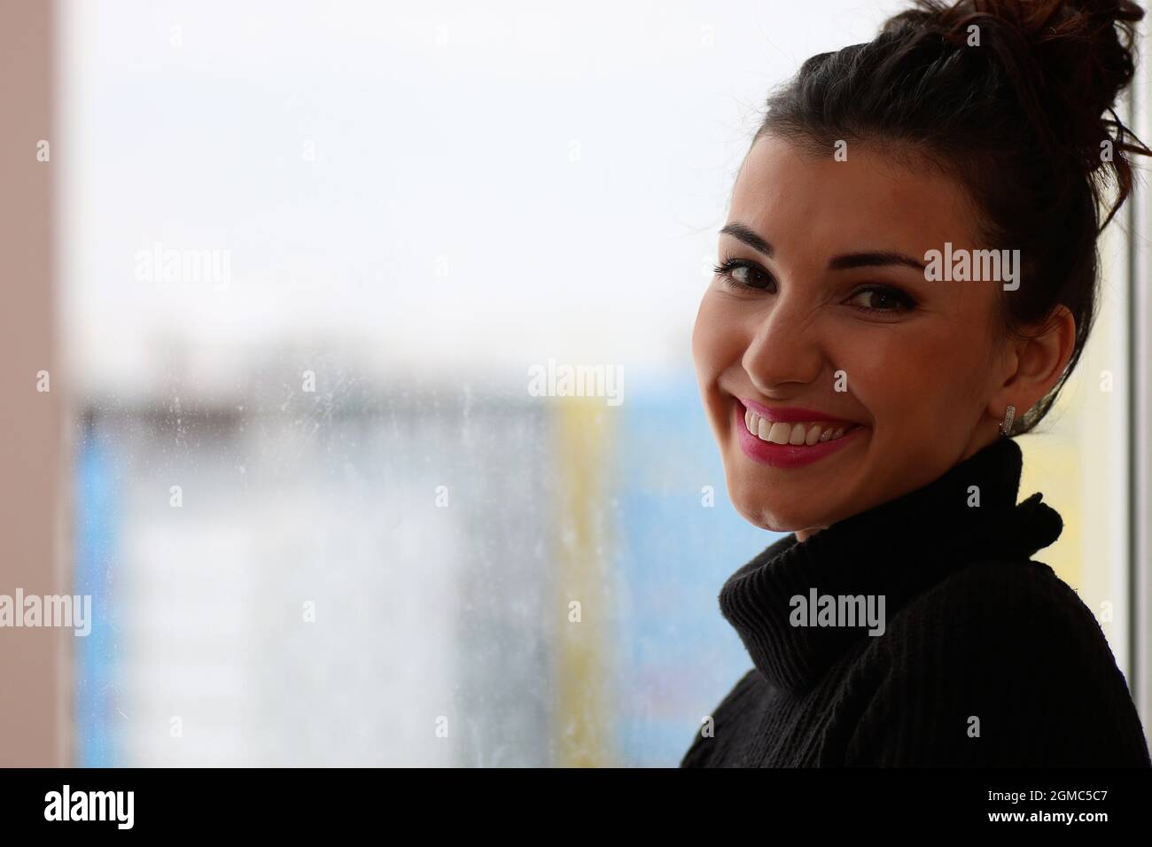 A young woman looks out the window of a new apartment Stock Photo - Alamy