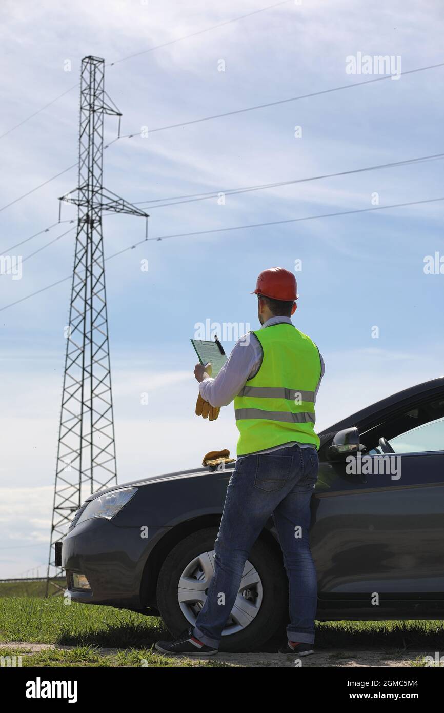An electrician in the fields near the power transmission line. The ...