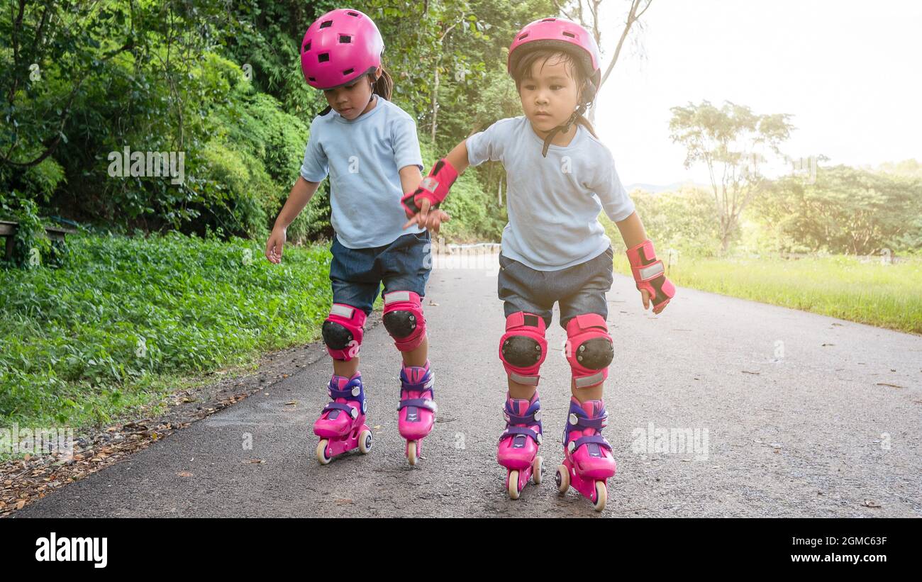 Two sibling sisters wearing protection pads and safety helmet ...