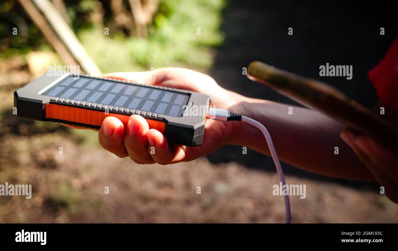 A rechargeable mobile power pack with solar panels in young female ...