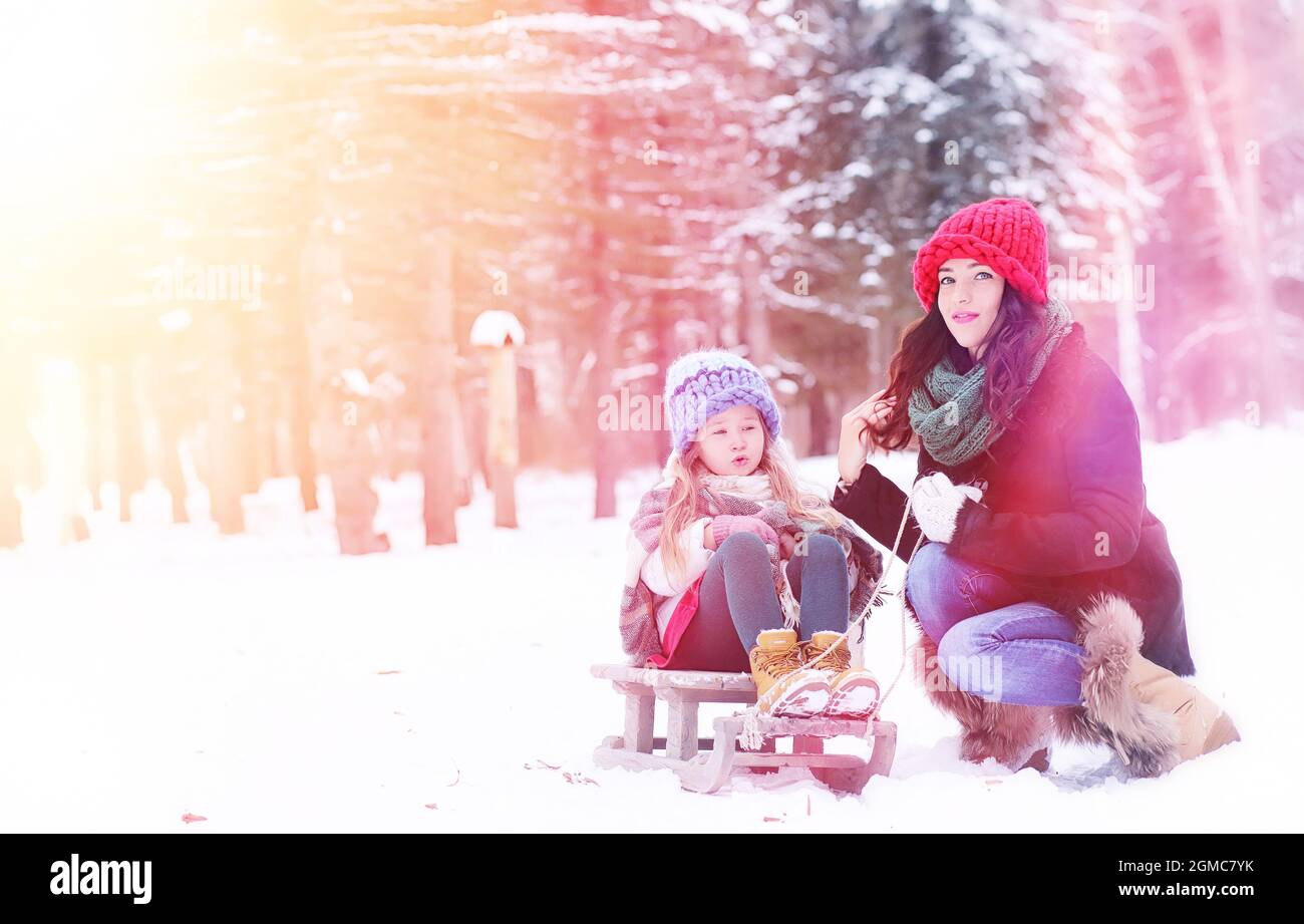 Winter fairy tale, a young mother and her daughter ride a sled in the ...