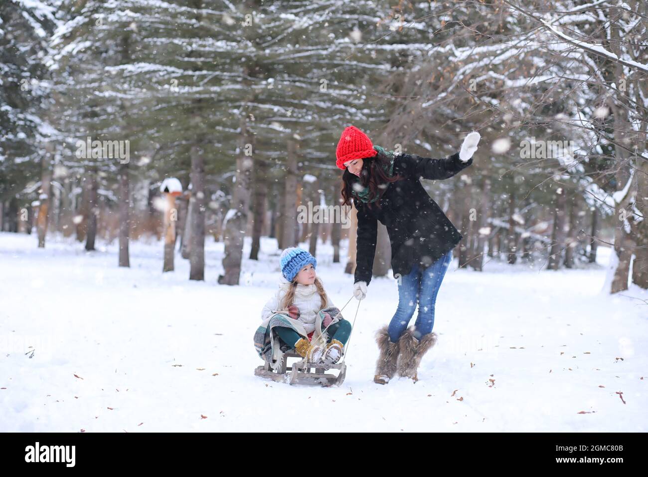 Winter fairy tale, a young mother and her daughter ride a sled in the ...