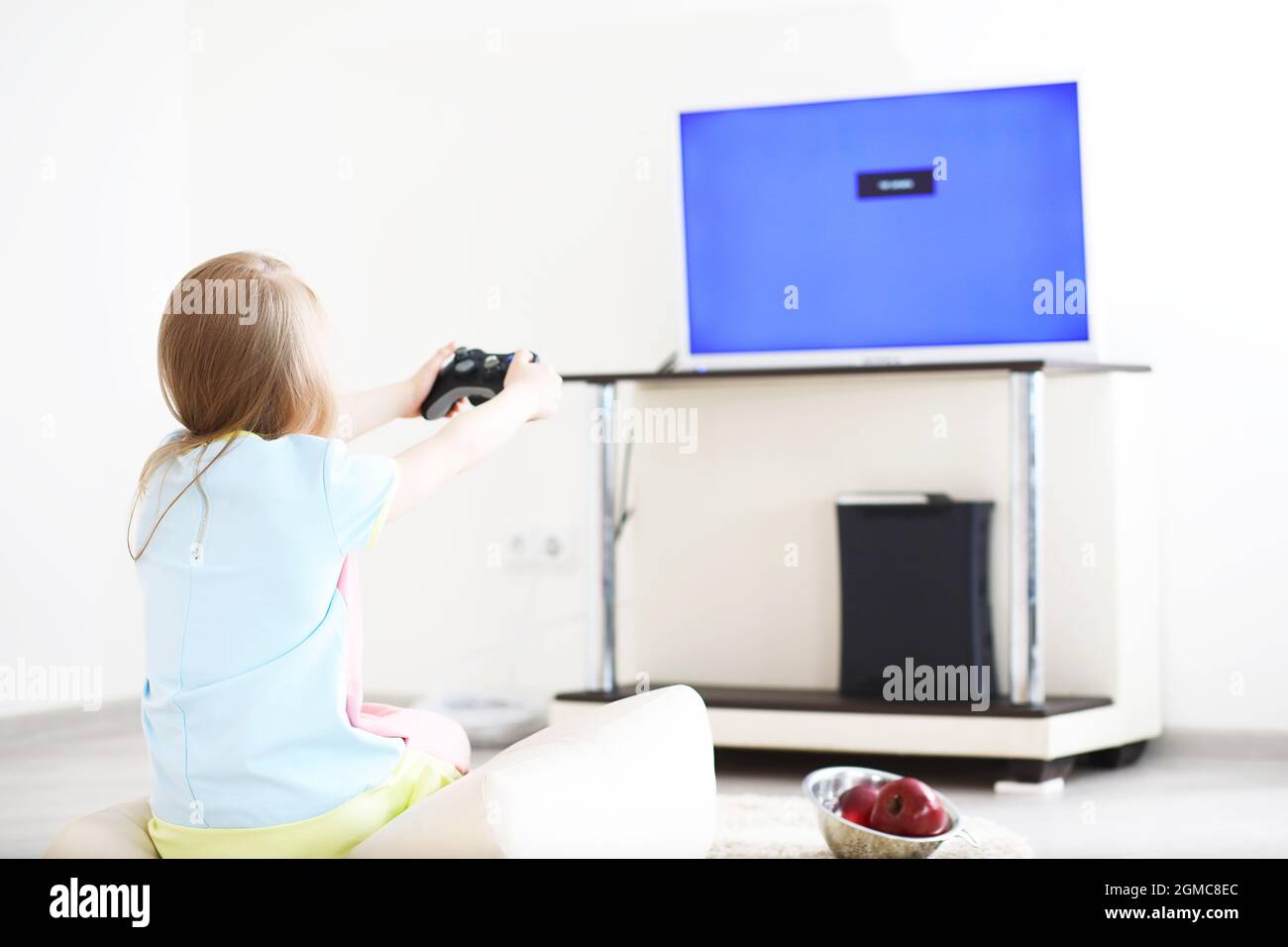Young girl playing in the console in front of the TV Stock Photo - Alamy