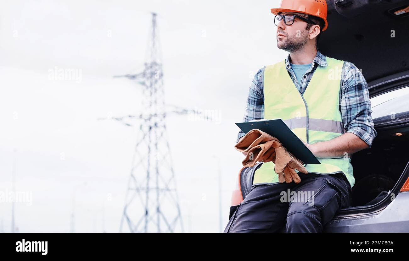 A man in a helmet and uniform, an electrician in the field ...