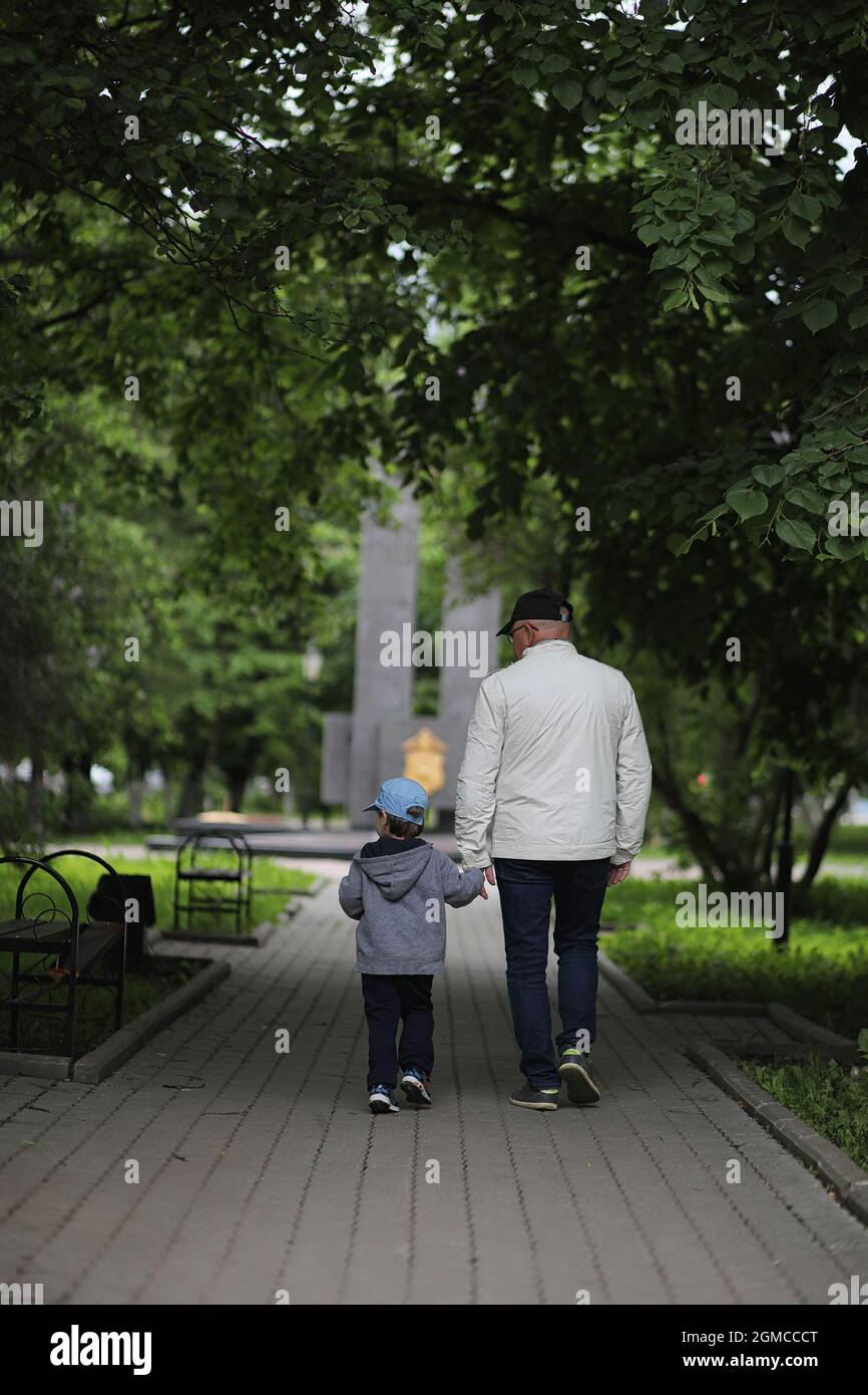 Grandpa is walking with her grandson in a spring park. Grandson and ...