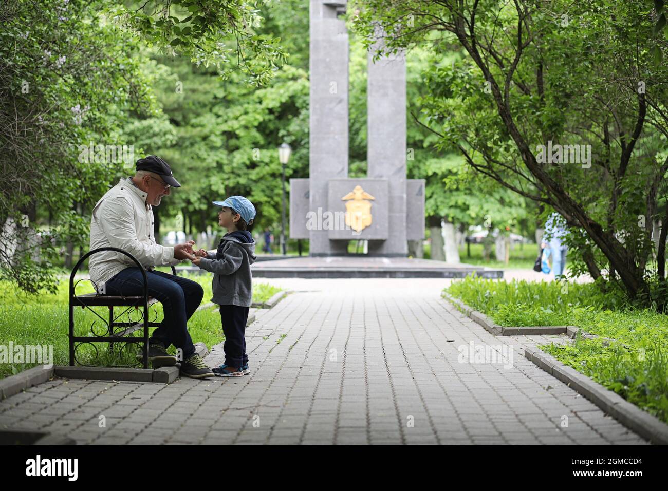 Grandpa is walking with her grandson in a spring park. Grandson and ...