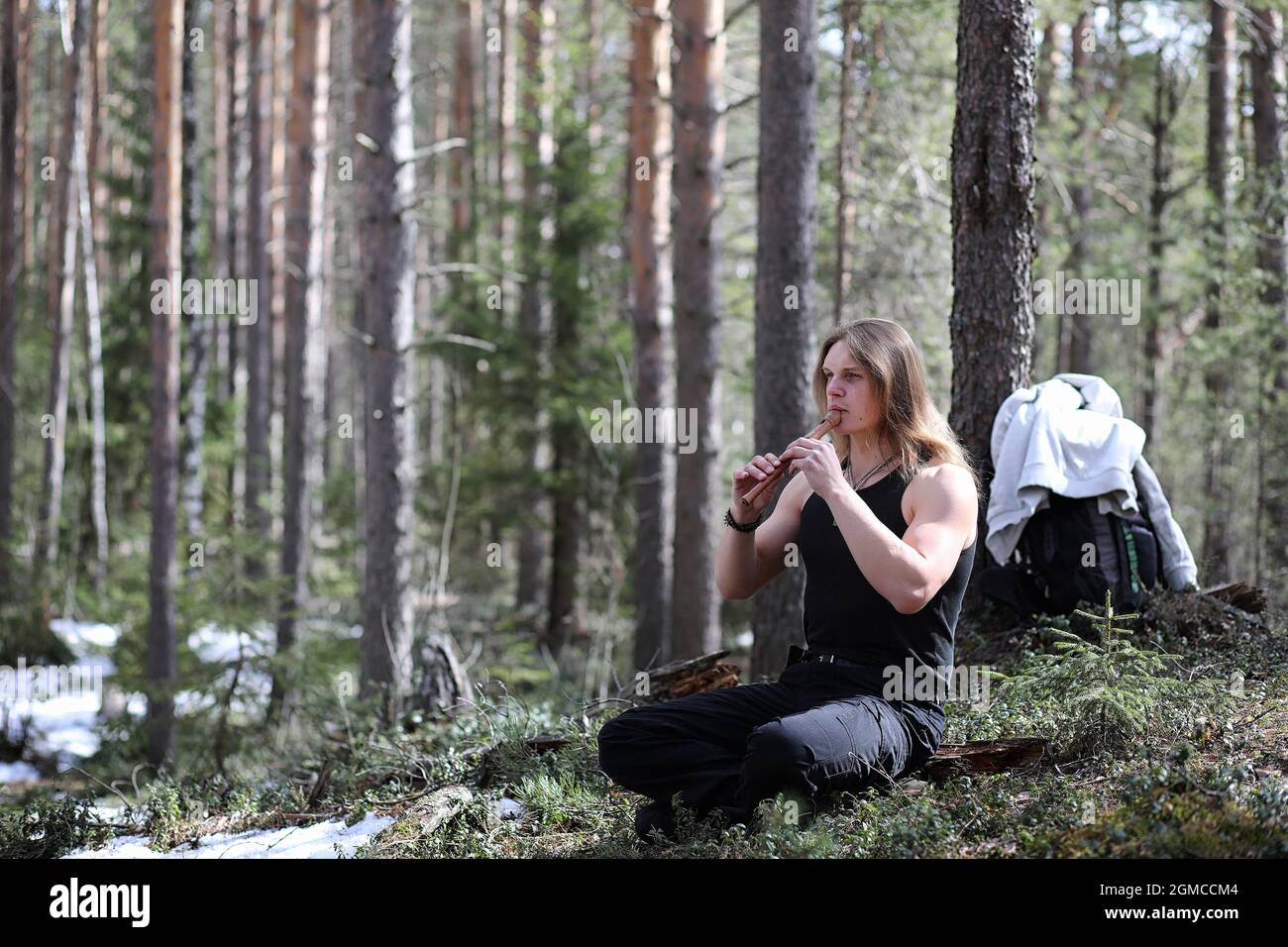 A musician with a tool in nature. Man is playing a flute in a pine ...