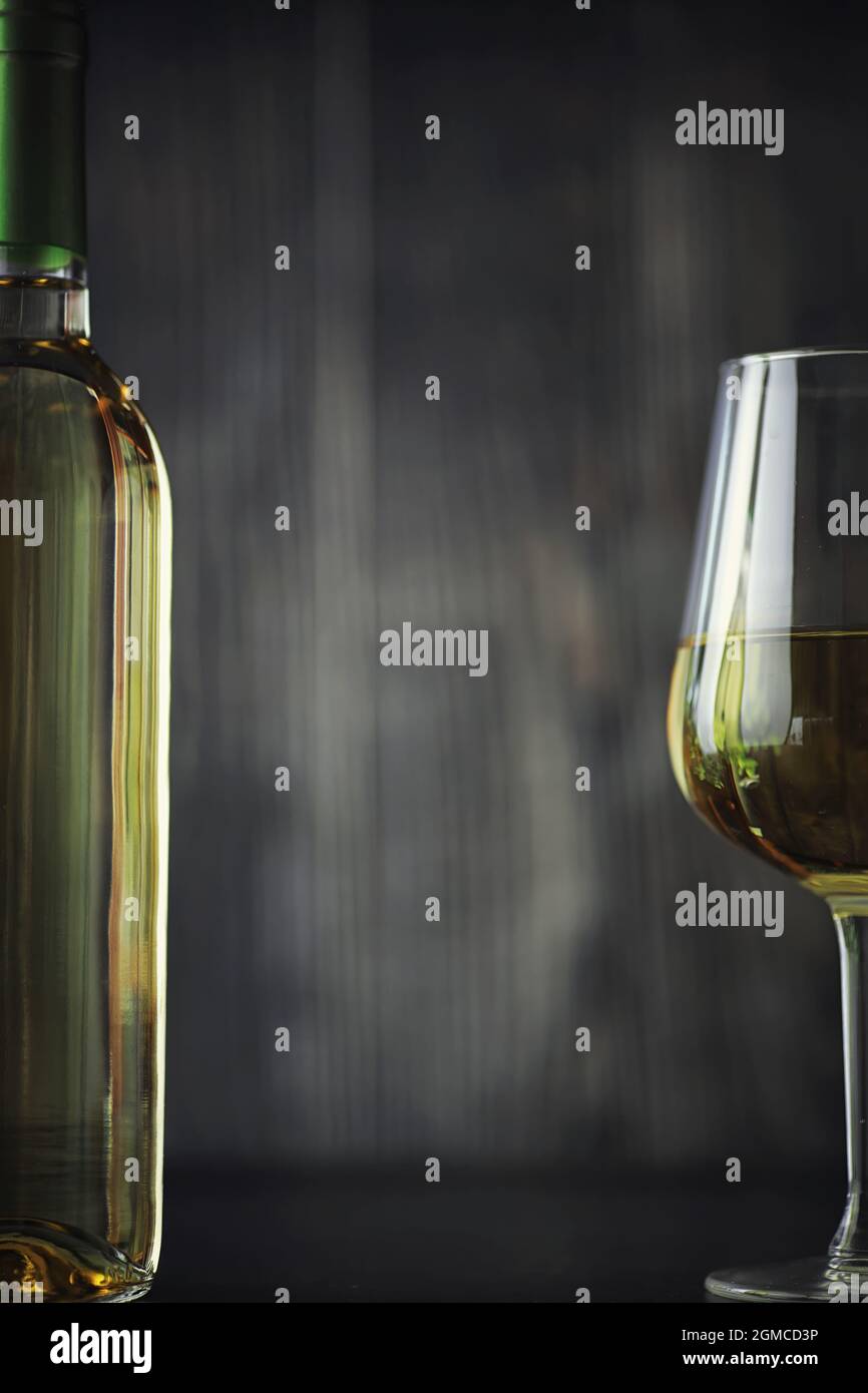 Transparent bottle of white dry wine on the table. White wine glass on ...