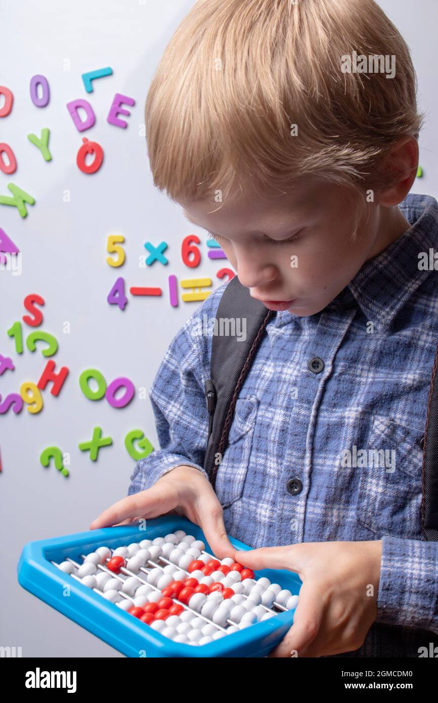 Front view of smart boy holding abacus against green chalkboard in a ...