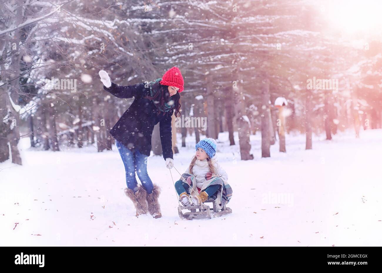 Winter fairy tale, a young mother and her daughter ride a sled in the ...