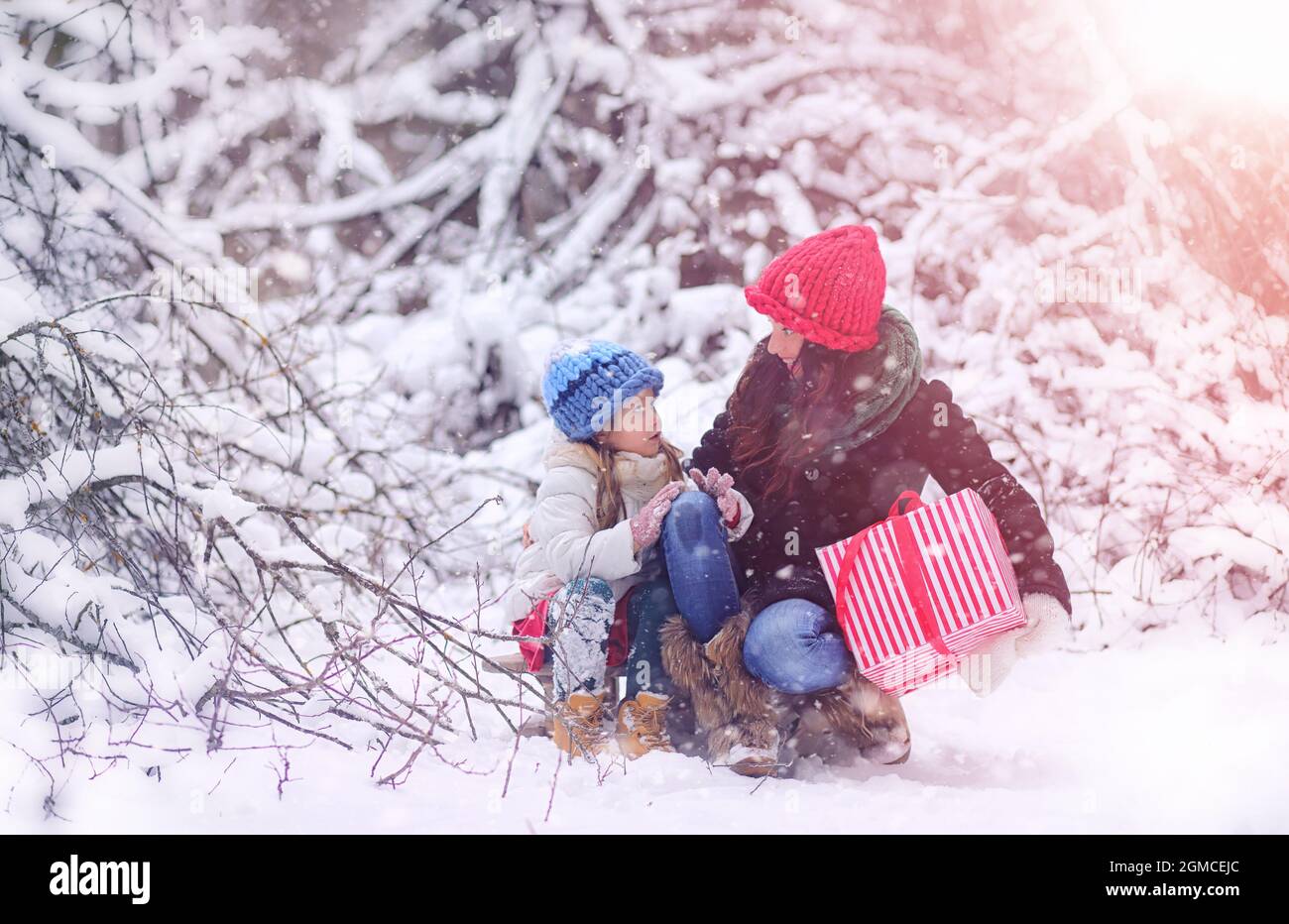 Winter fairy tale, a young mother and her daughter ride a sled in the ...