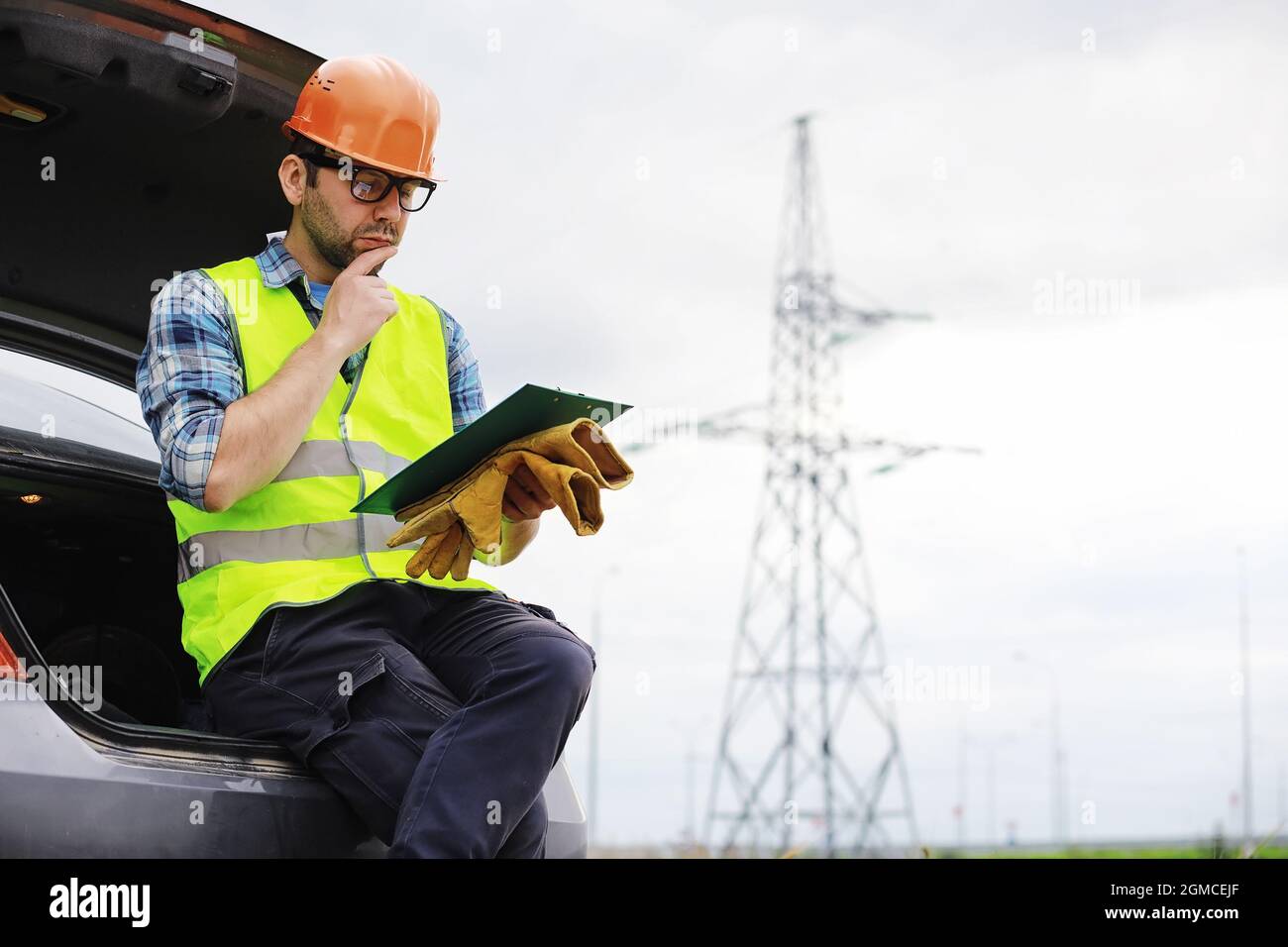 A man in a helmet and uniform, an electrician in the field ...