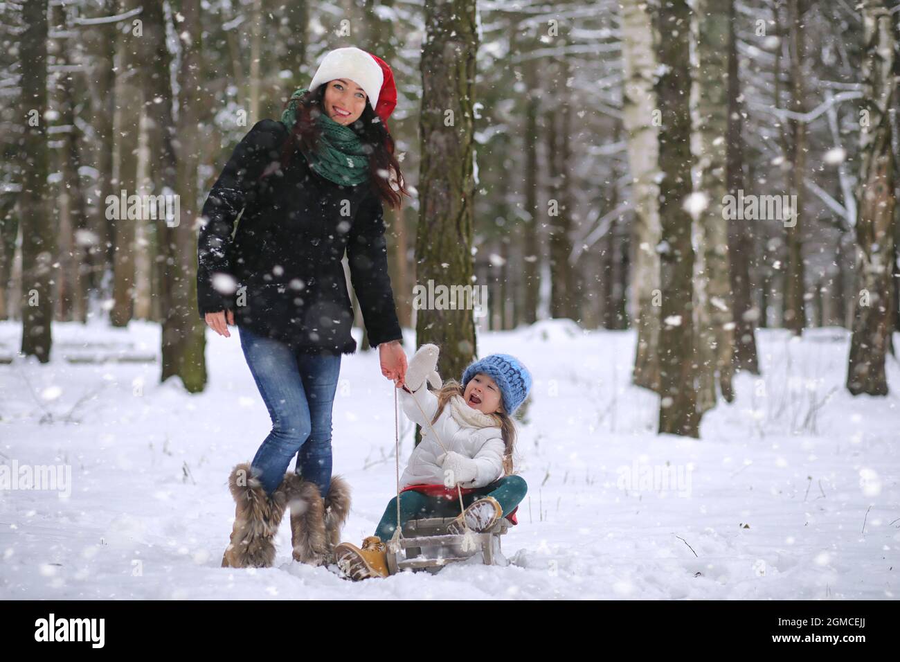 Winter fairy tale, a young mother and her daughter ride a sled in the ...