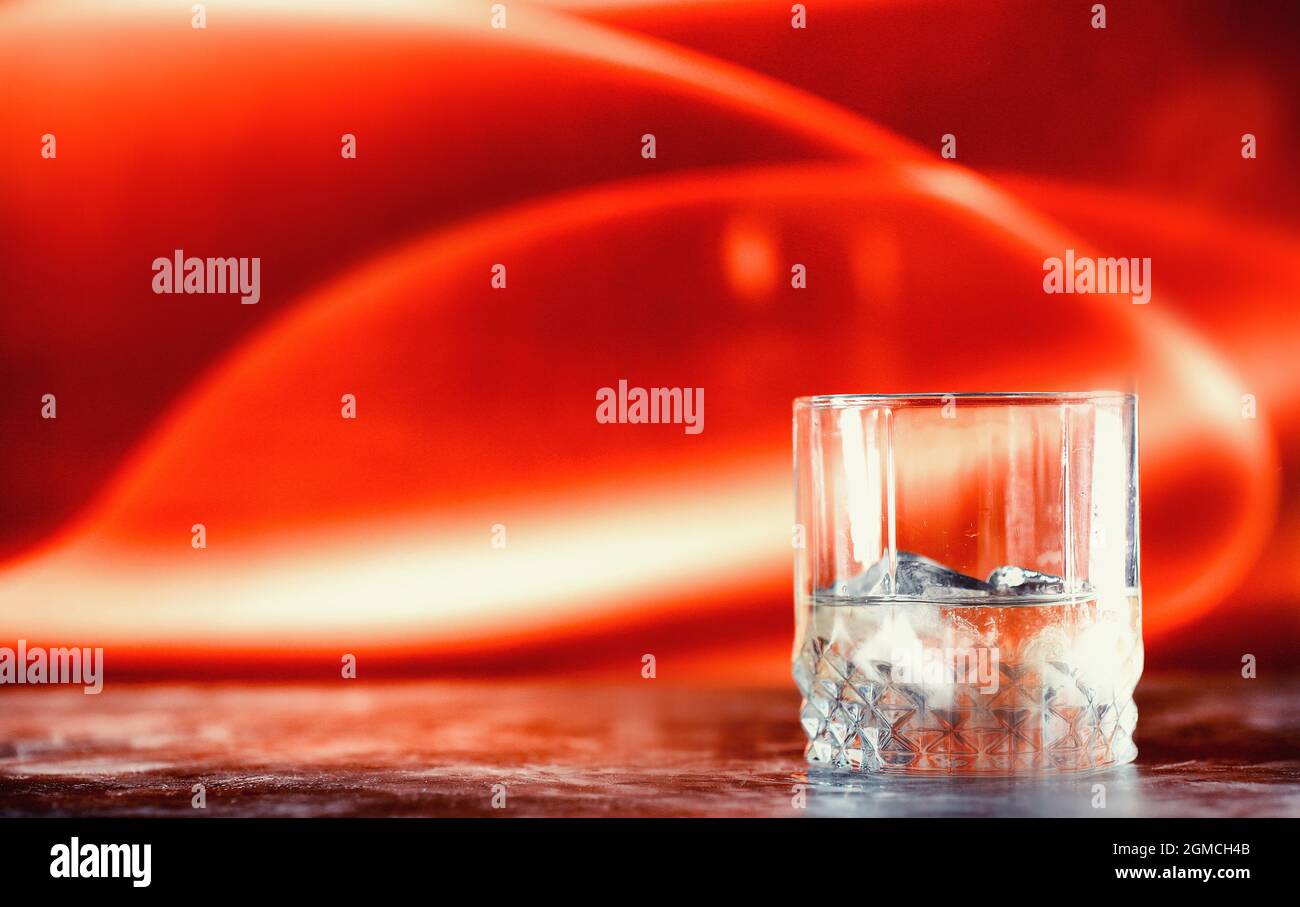 A glass of hard alcohol with ice on a bar counter. Whiskey with soda in ...