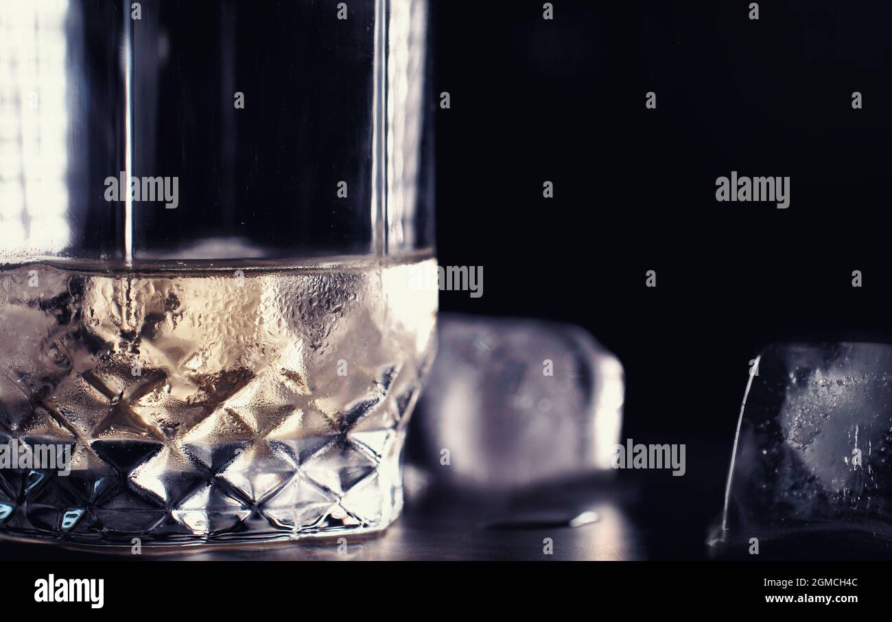 A glass of hard alcohol with ice on a bar counter. Whiskey with soda in ...