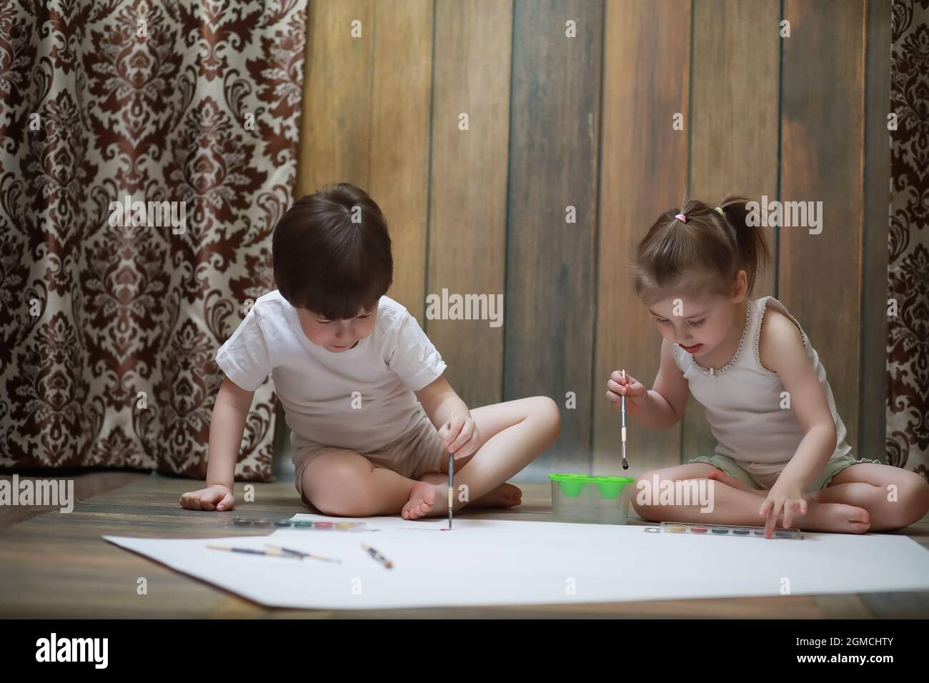 Little children paint on a large sheet of paper on the floor Stock ...