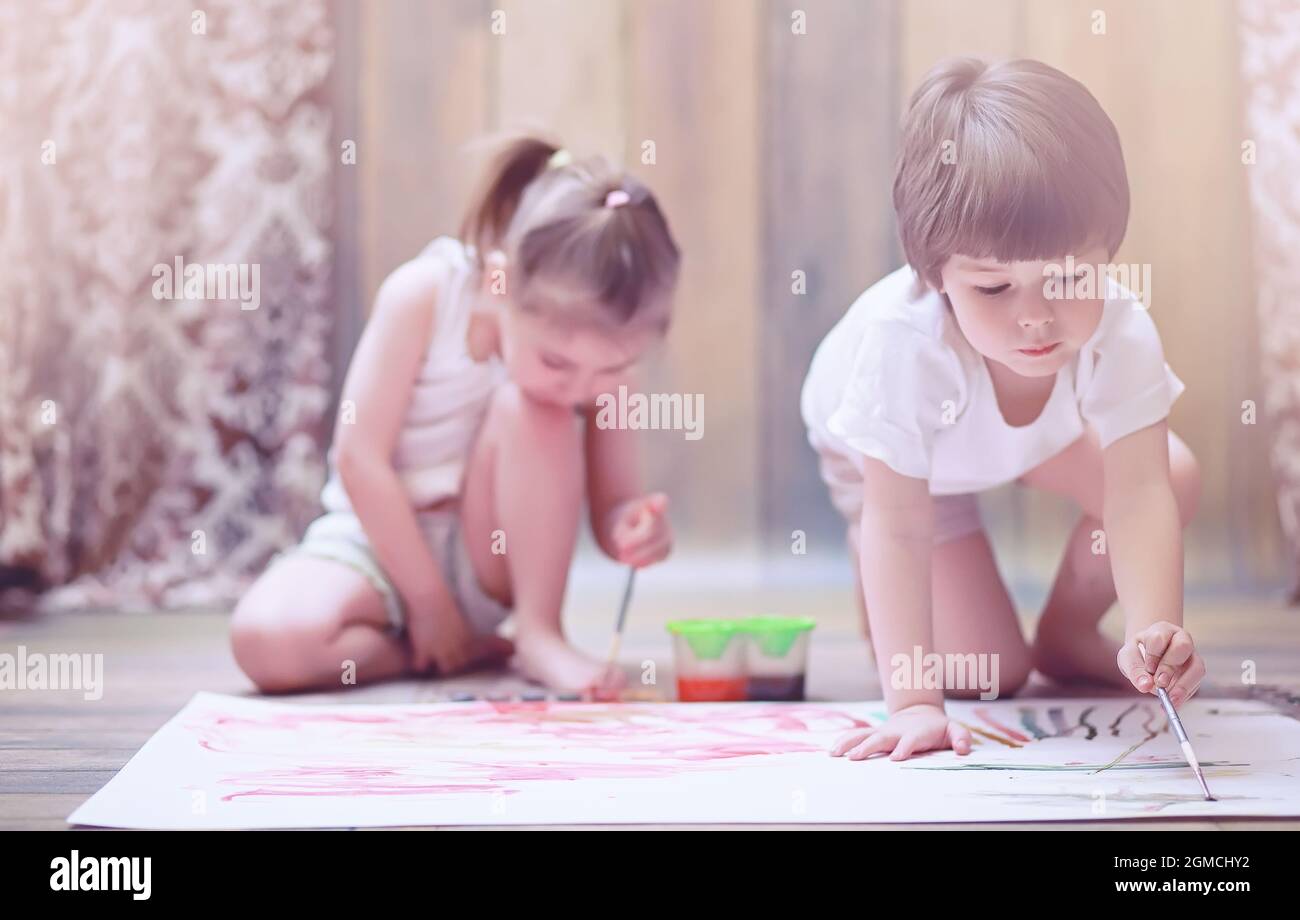 Little children paint on a large sheet of paper on the floor Stock ...