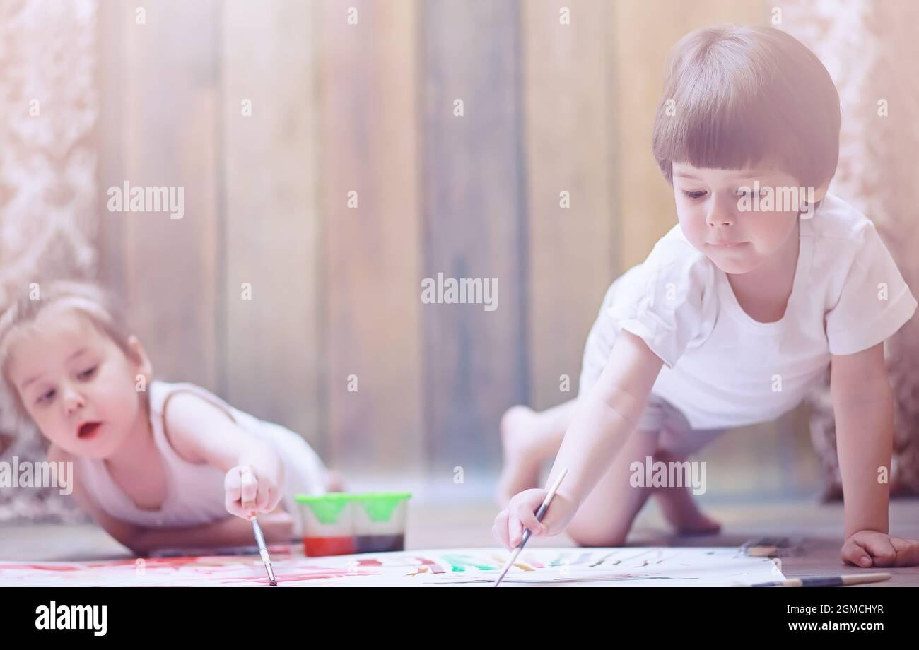 Little children paint on a large sheet of paper on the floor Stock ...