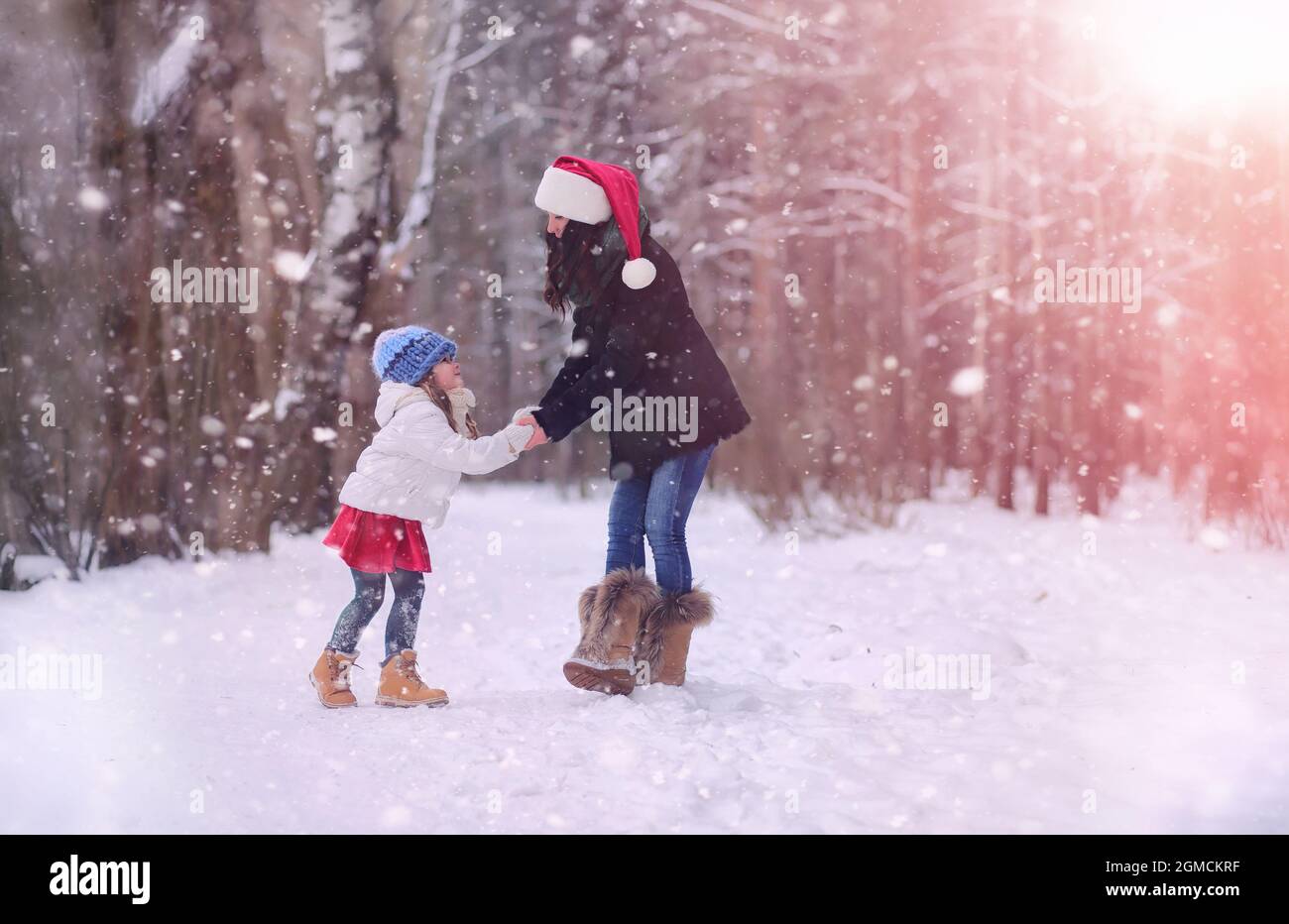 Winter fairy tale, a young mother and her daughter ride a sled in the ...