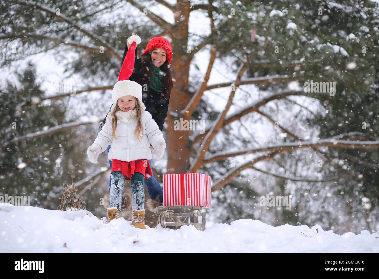 Winter fairy tale, a young mother and her daughter ride a sled in the ...