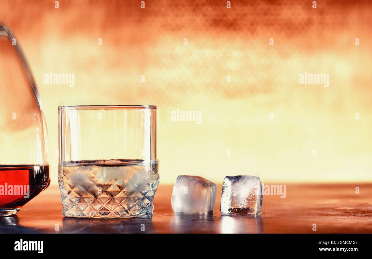 A glass of hard alcohol with ice on a bar counter. Whiskey with soda in ...